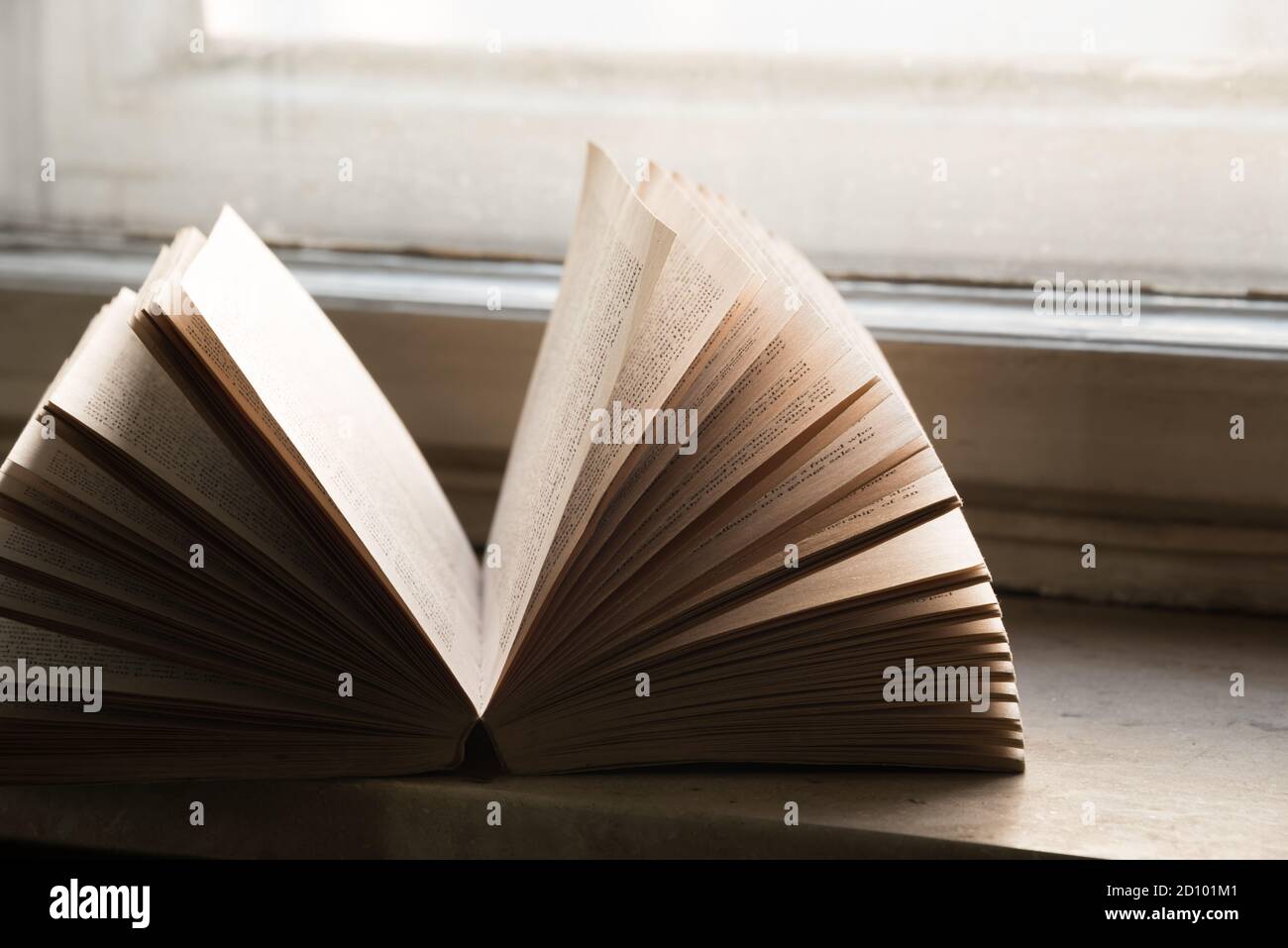 Open book with fanned out pages, on window sill, with warm light Stock ...