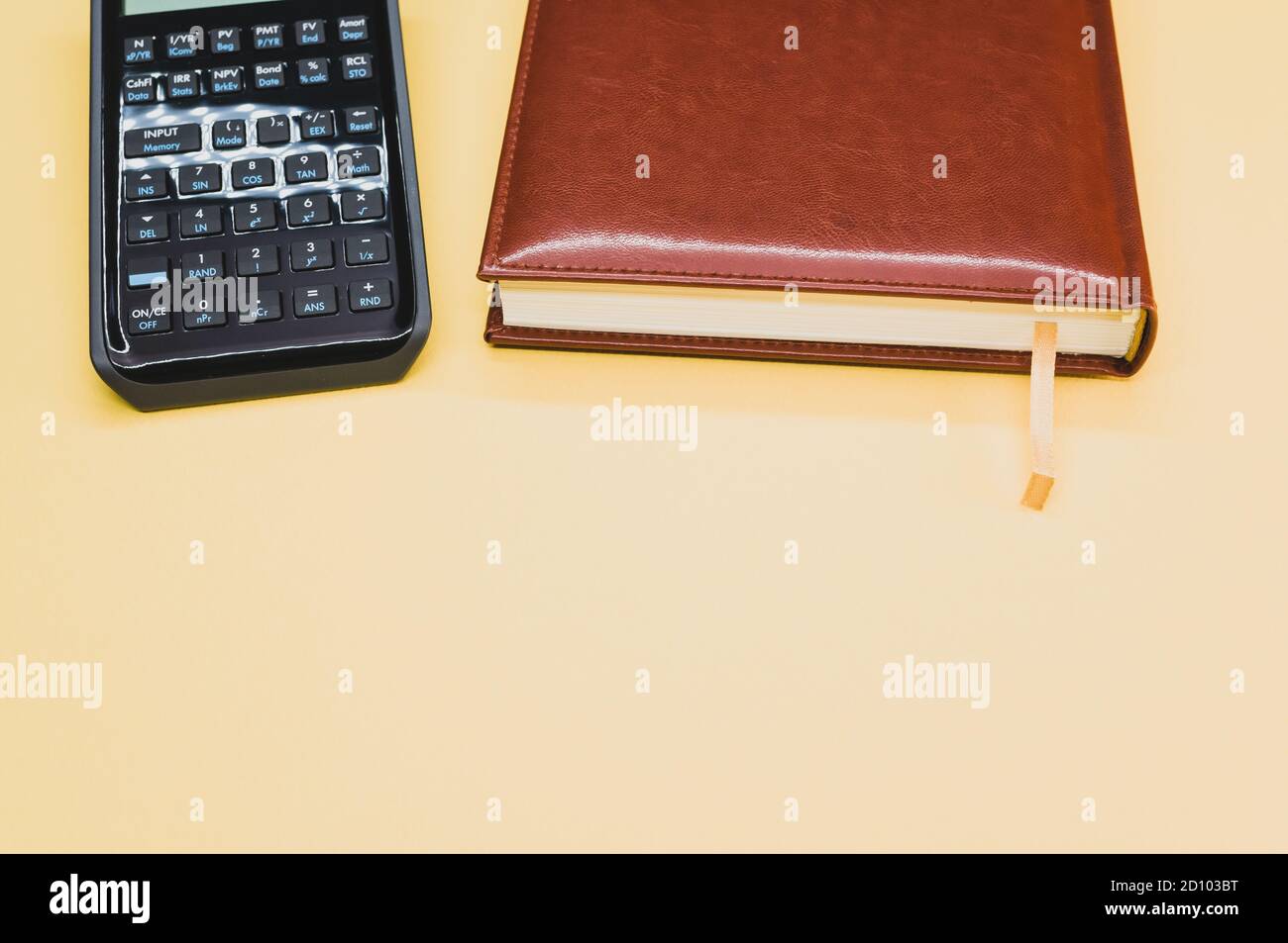 Scientific calculator next to a notebook on pastel yellow background ...