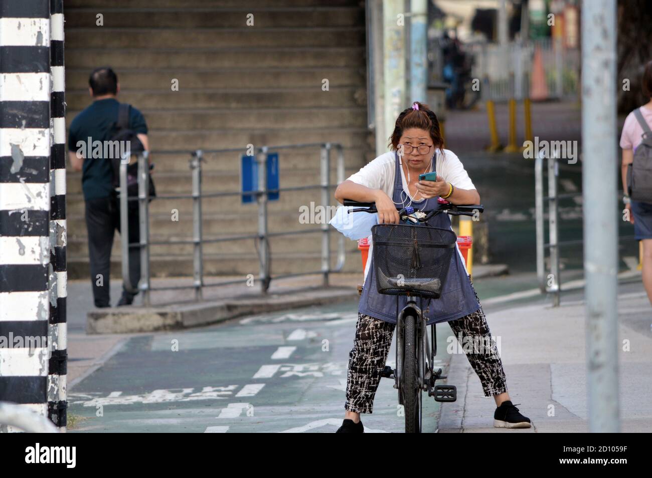 Middle-aged woman cyclist resting along a cycle track in Yuen Long, New ...
