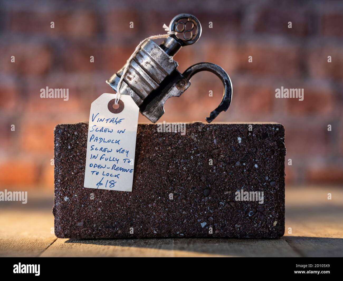 Vintage Barrel Padlock with screw key resting on brick with brick ...