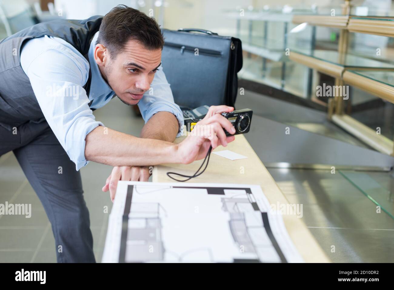 portrait of serious concentrated architect taking a photo of plans ...