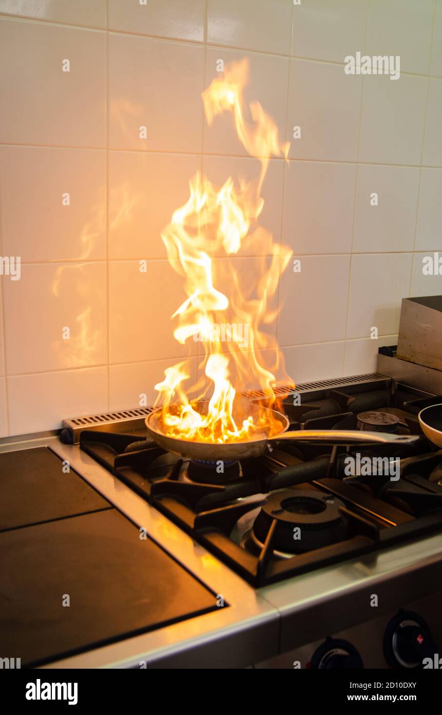 Pan on fire in kitchen presenting fire hazard Stock Photo - Alamy