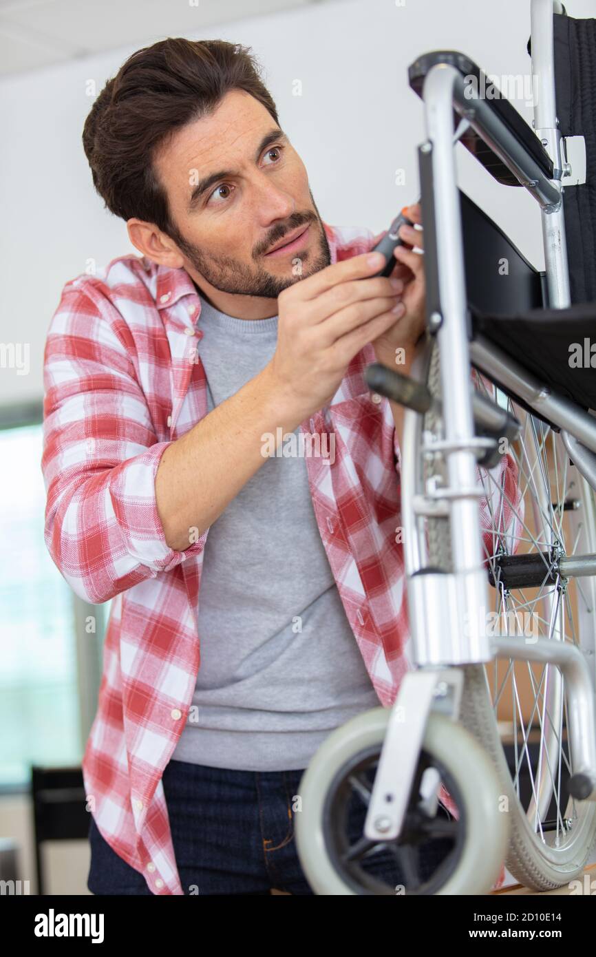 handsome adult repairer fixing wheelchair wheel Stock Photo - Alamy
