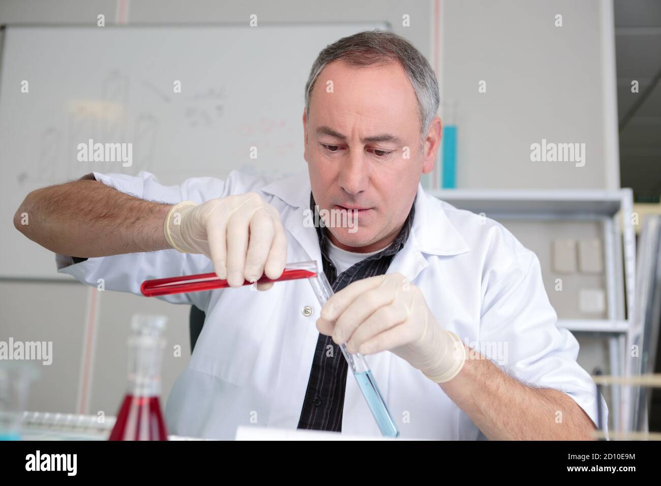 male chemist looking at a tube with a blood sample Stock Photo - Alamy