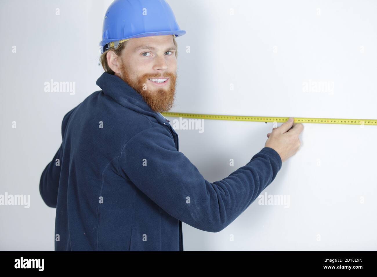 happy man measuring a wall using a ruler Stock Photo - Alamy