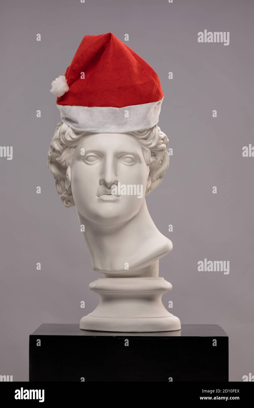 White Plaster Statue of Apollo Belvedere in a red cap of Santa Claus ...