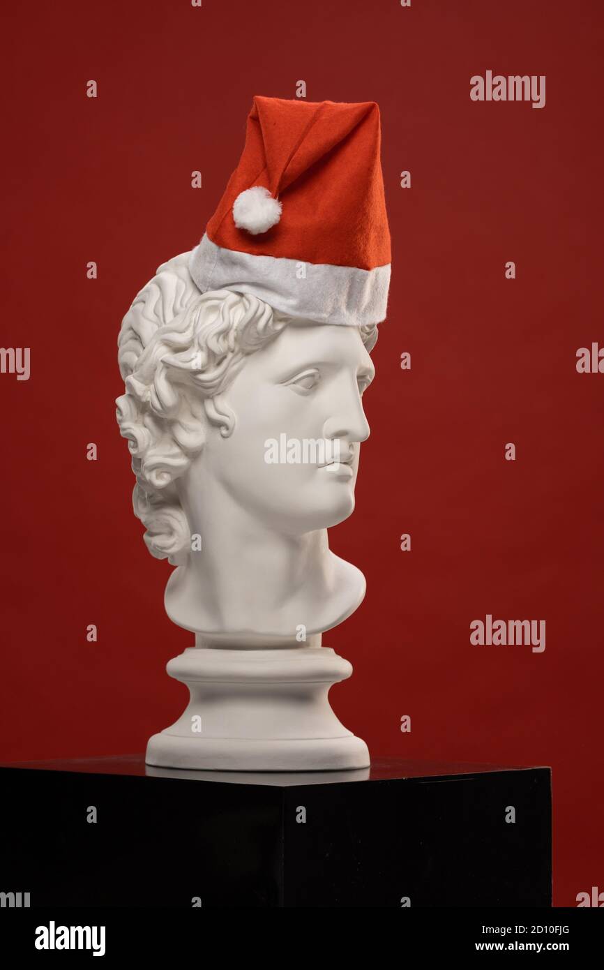 White Plaster Statue of Apollo Belvedere in a red cap of Santa Claus ...