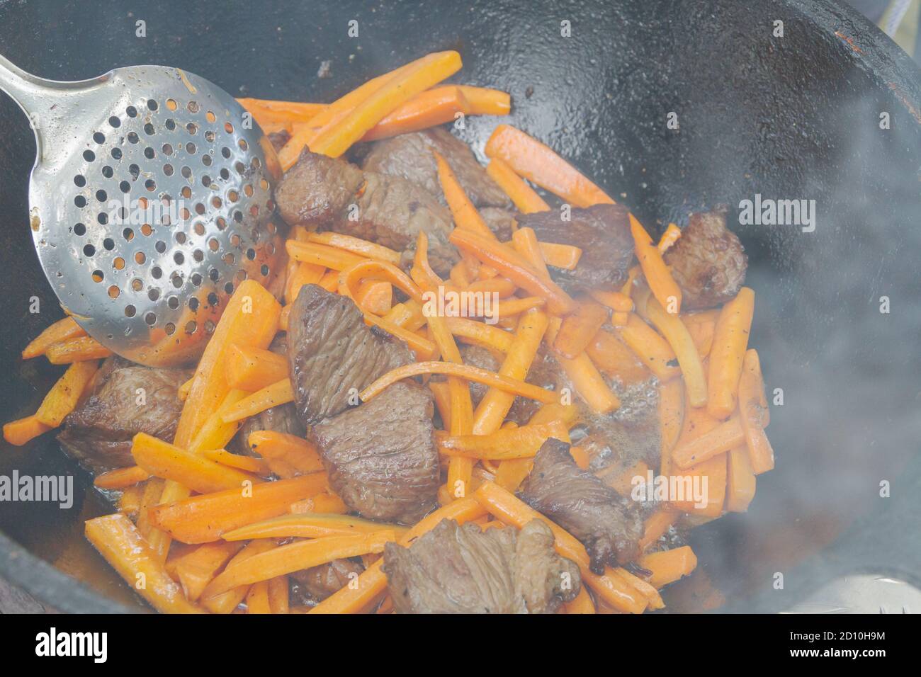 Cooking pilaf in a cauldron on the grill outside in the summer Stock ...