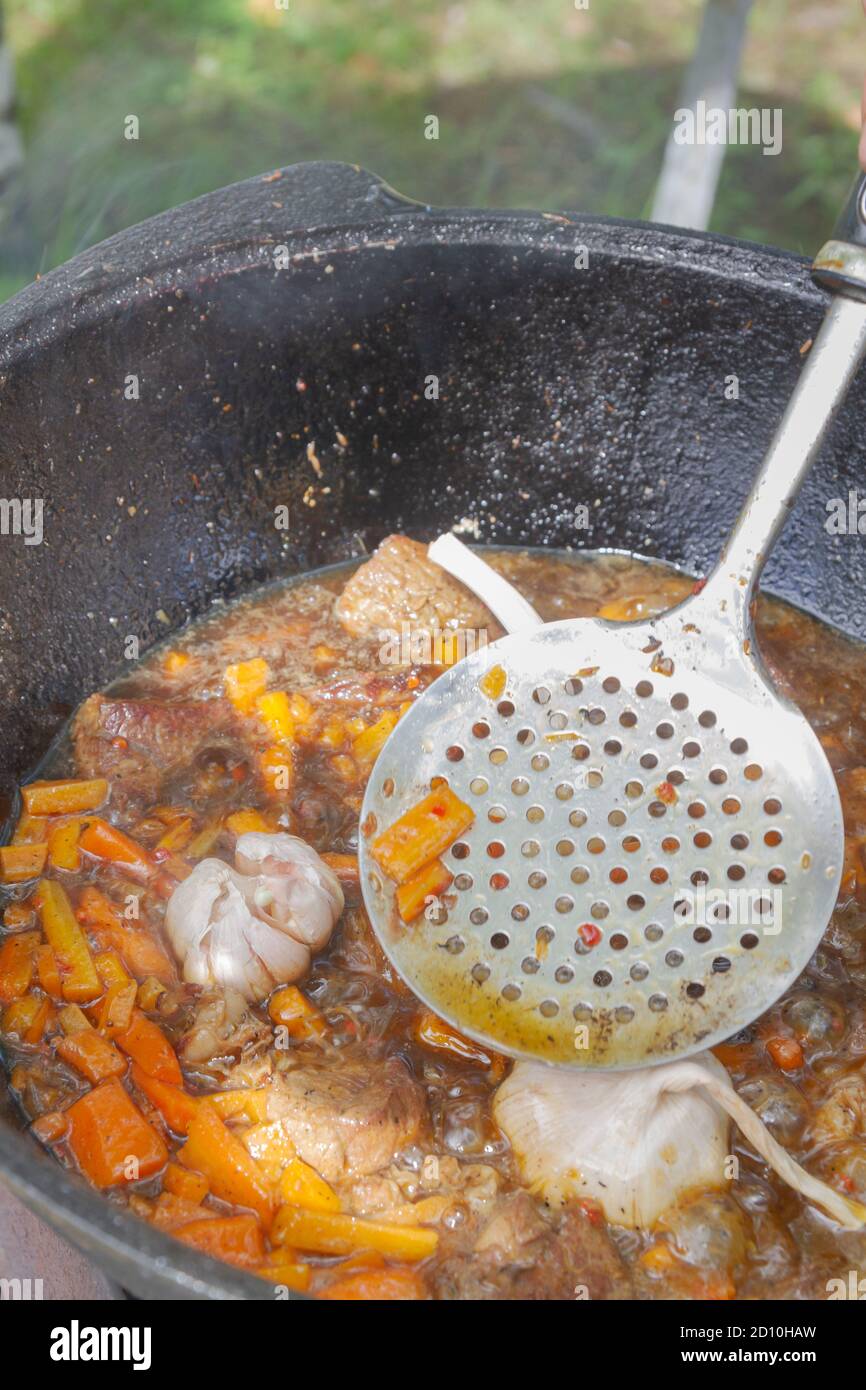 Cooking pilaf in a cauldron on the grill outside in the summer Stock ...