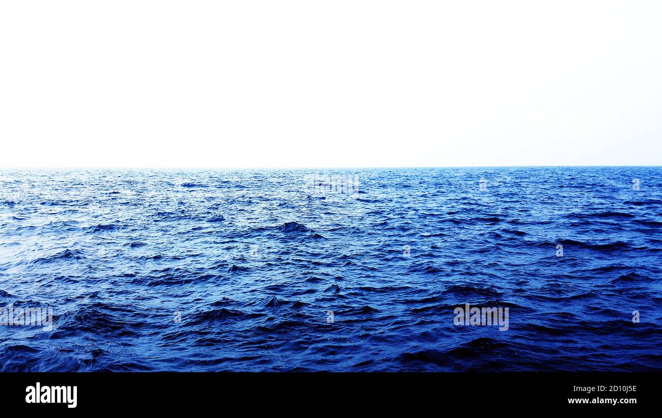 The open deep blue ocean water against the white sky. Beautiful ...