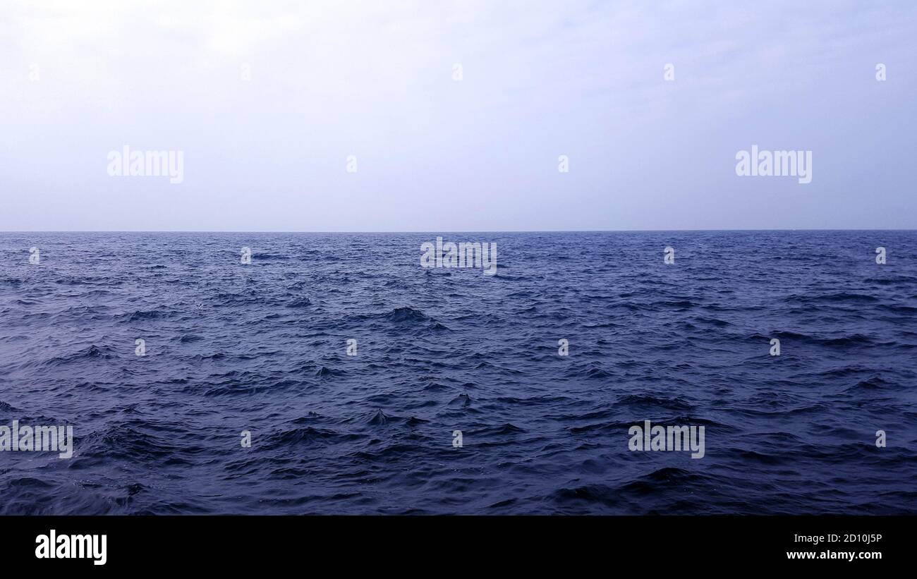 The open deep blue ocean water against the white sky. Beautiful ...