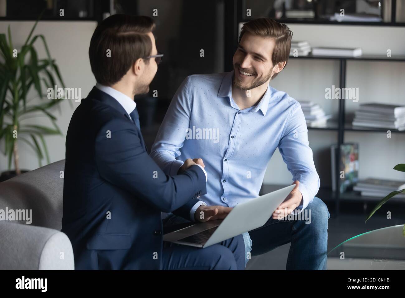 Smiling young employee shaking hands with pleasant ceo executive ...