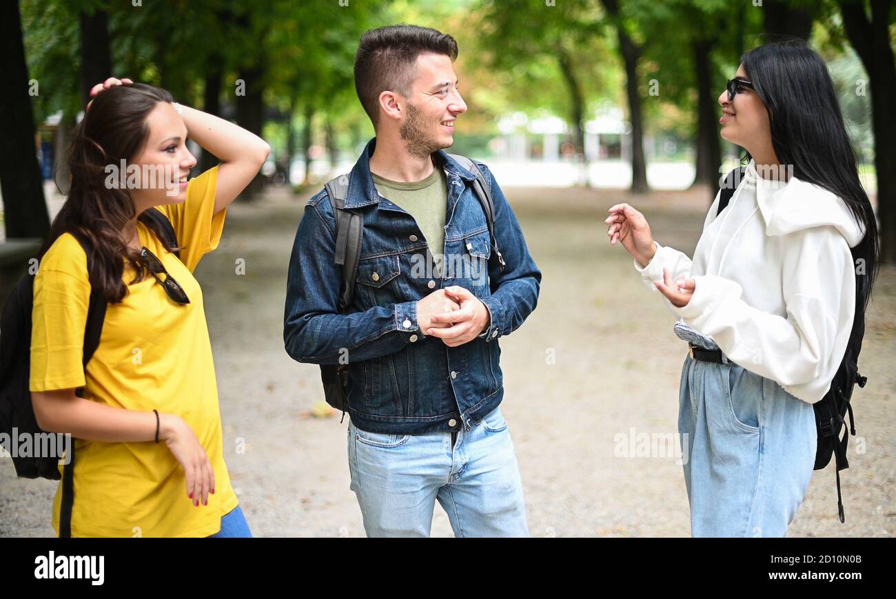 Three students talking to each other outdoor in a college courtyard ...