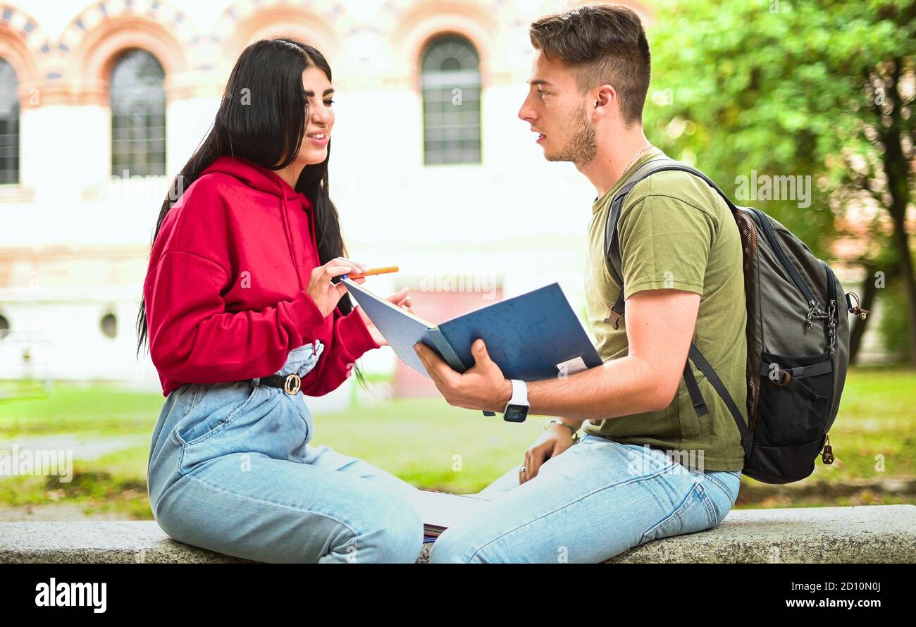 Two students studying together sitting on a bench outdoor Stock Photo ...