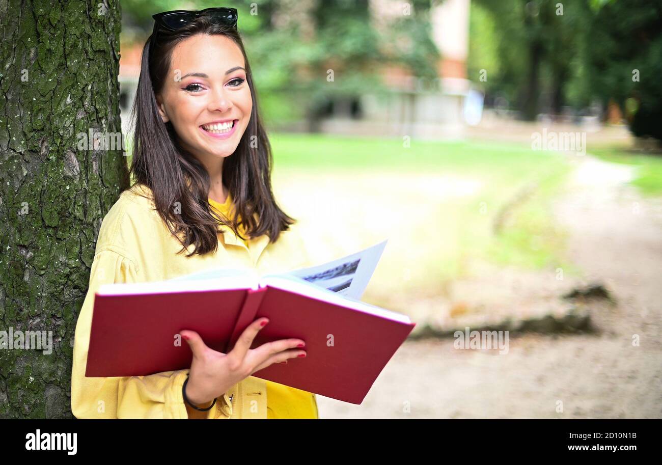 Beautiful female student reading a book outdoor Stock Photo - Alamy
