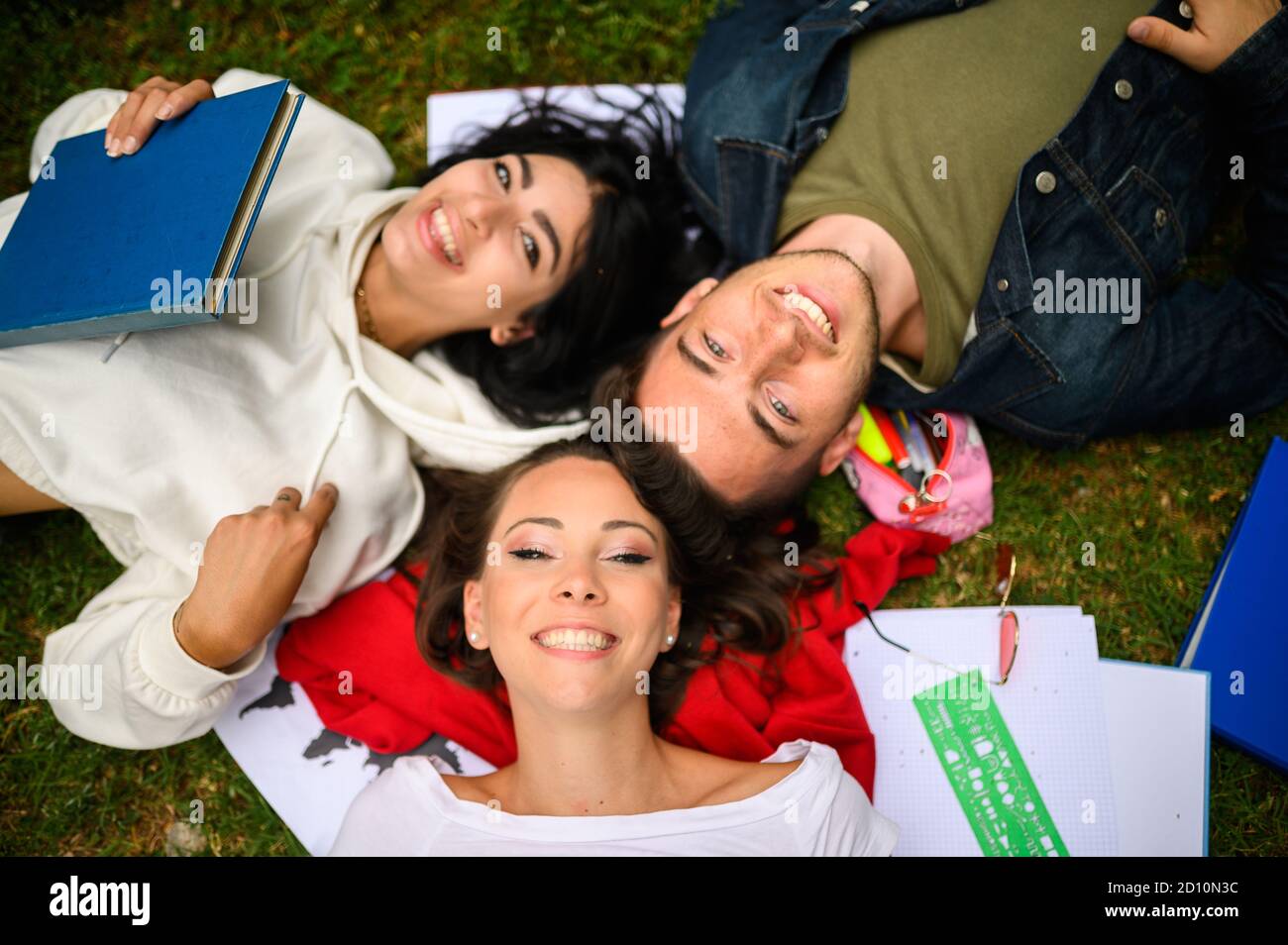 Three students lying on the grass and smiling Stock Photo - Alamy