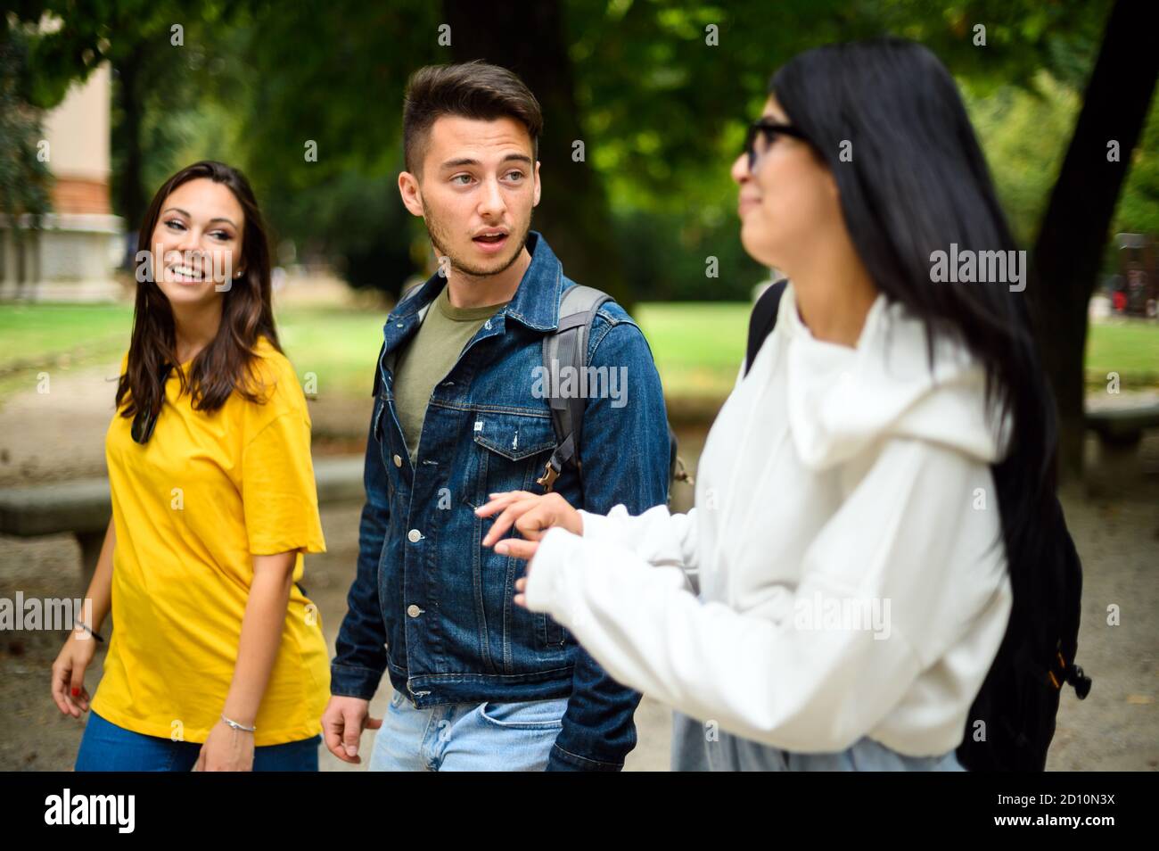 Three students talking to each other outdoor in a college courtyard ...
