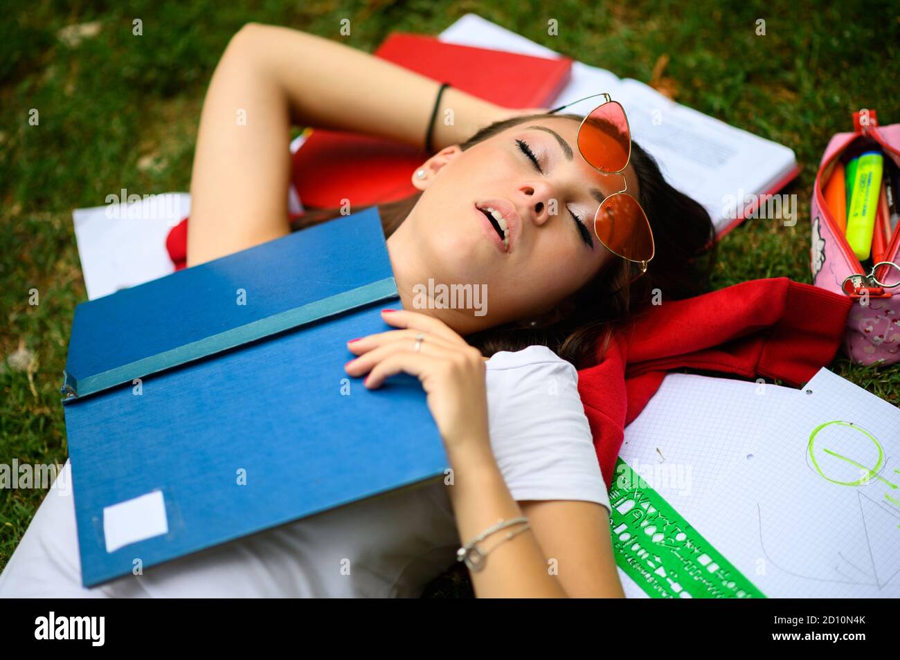 Female student sleeping on the grass with a book covering her Stock ...