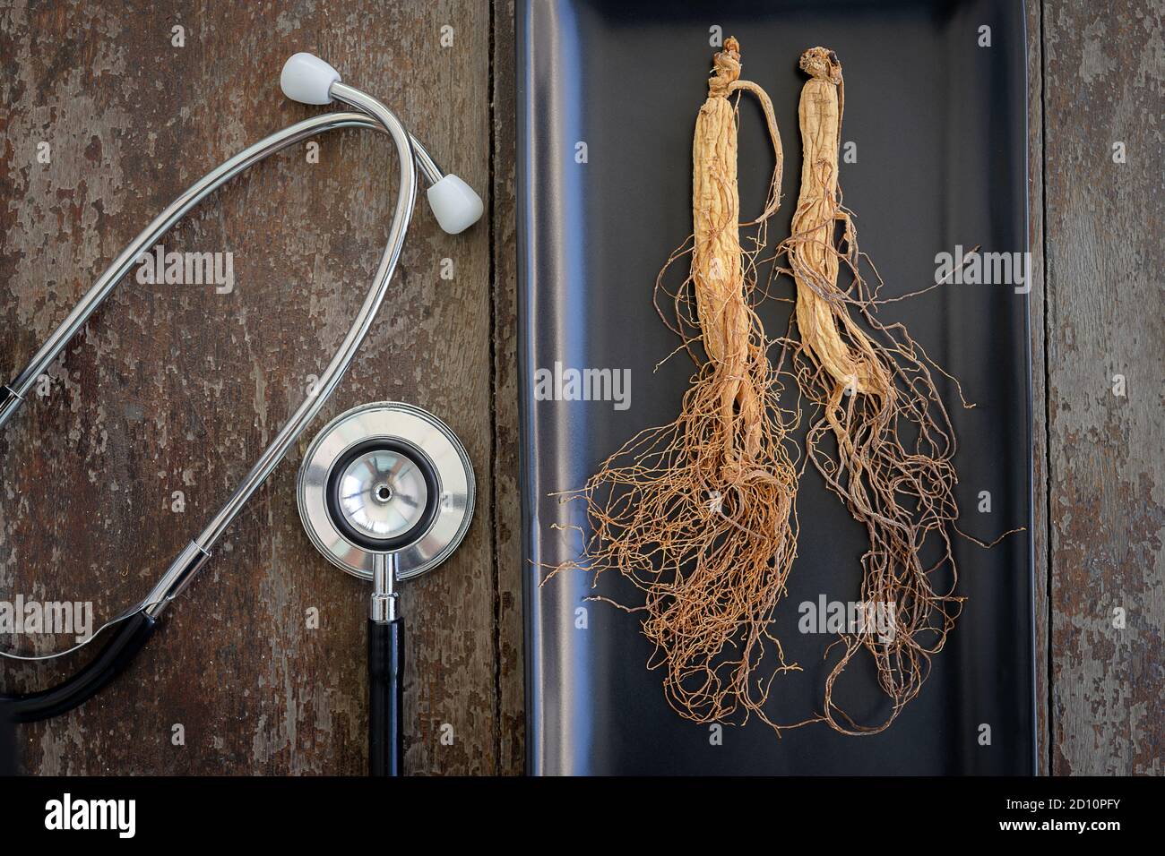 Dry ginseng on black plate with stethoscope on the wood background ...