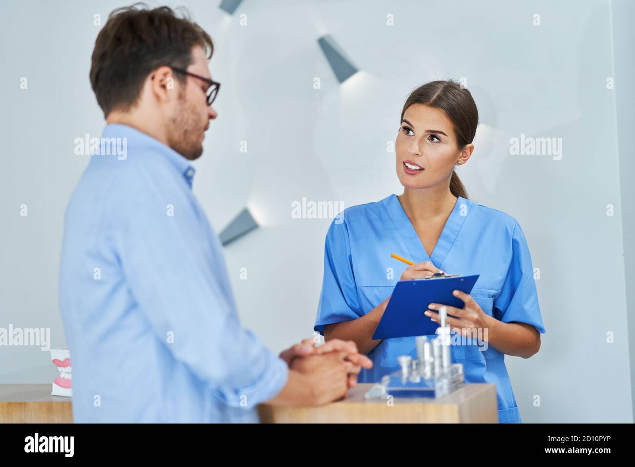Patient signing documents in dental clinic Stock Photo - Alamy