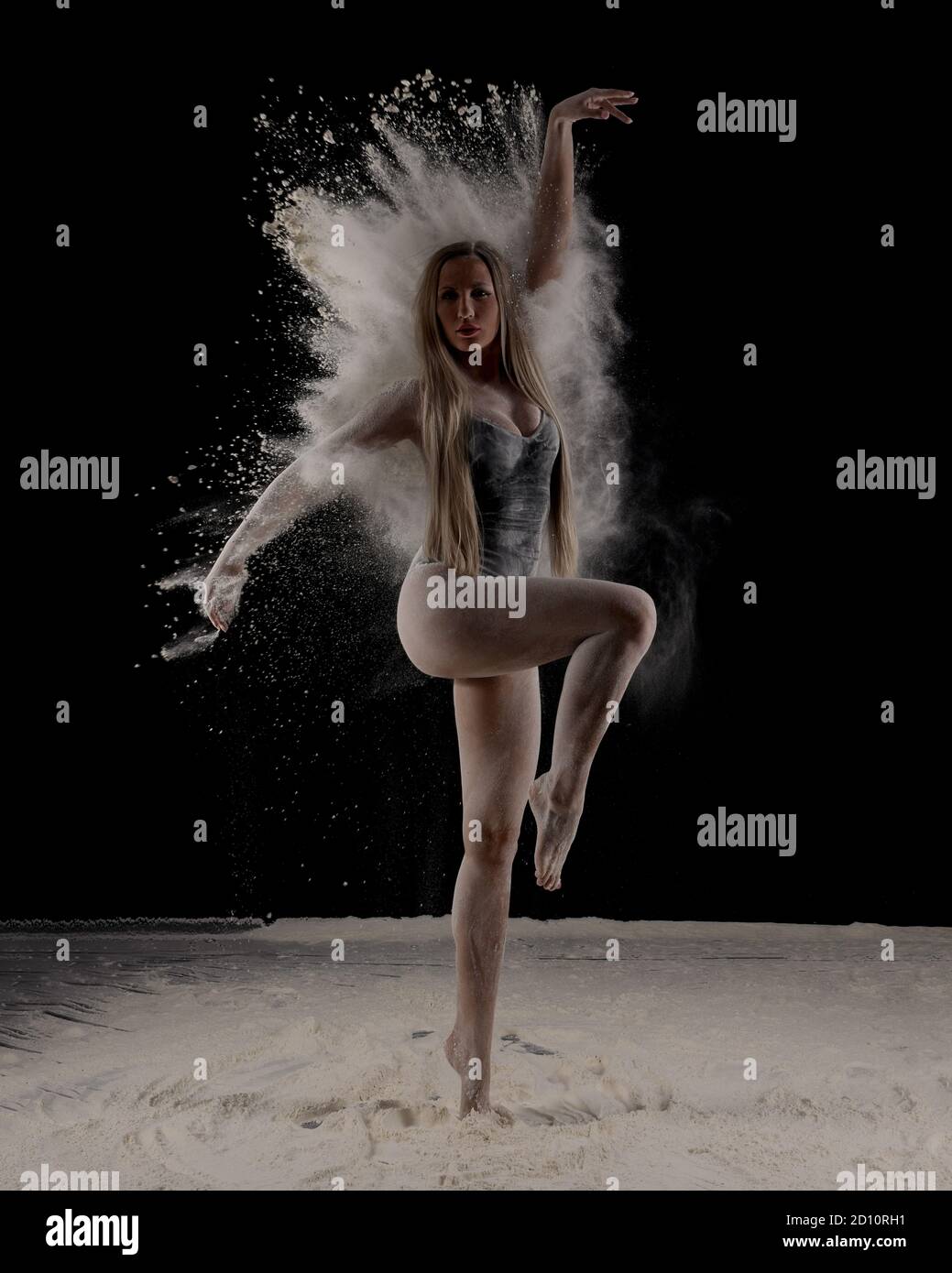 Beautiful sensual fit slim dancer in black body with long blond hair throwing dust, flour ...