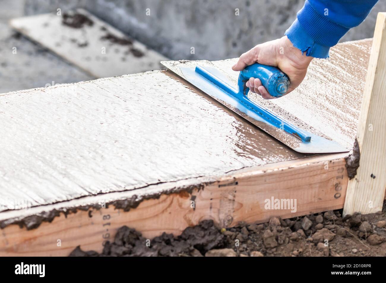 Construction Worker Using Trowel On Wet Cement Forming Coping Around ...