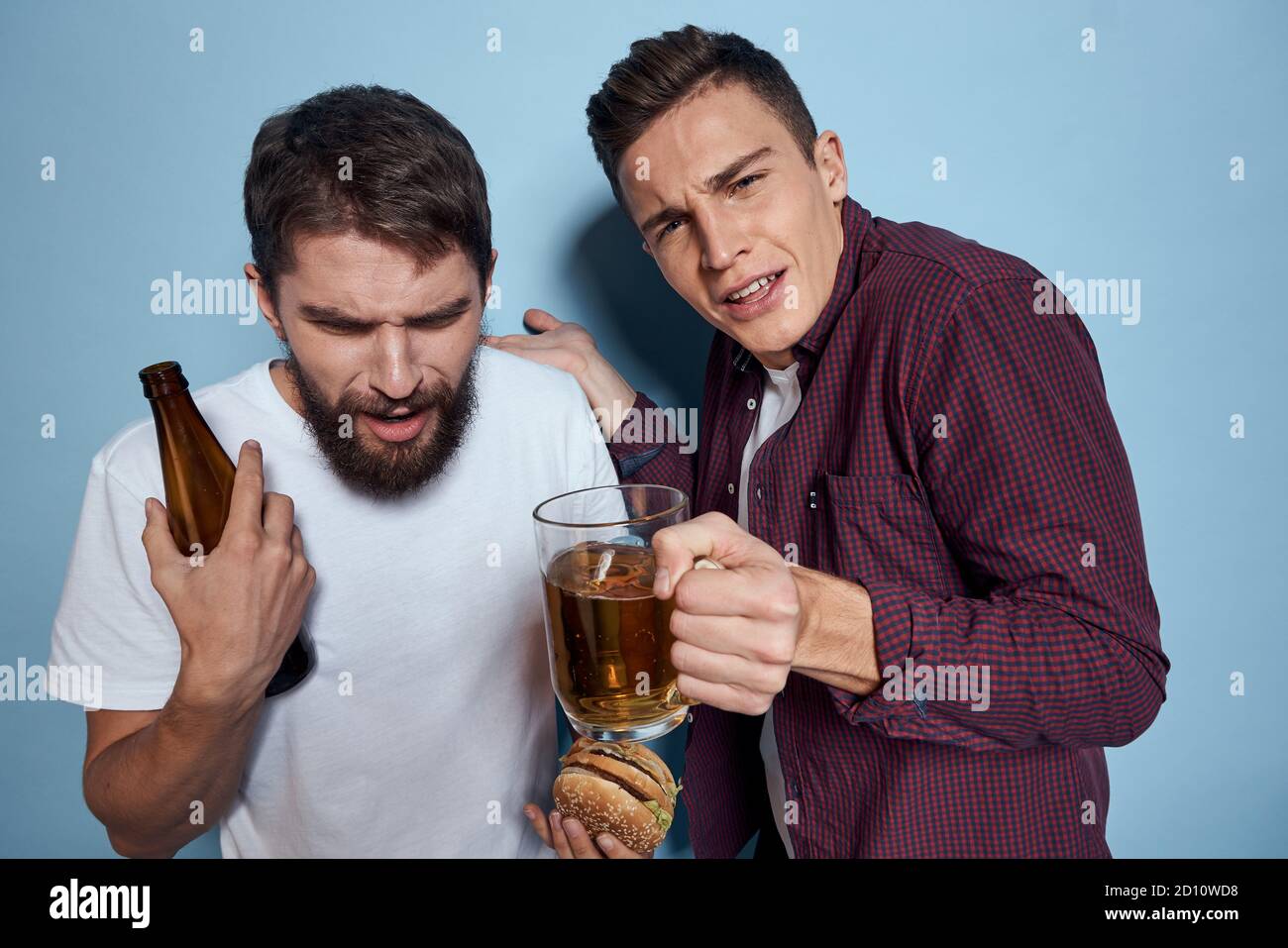 Two cheerful drunk friends drinking beer lifestyle emotions on a blue ...