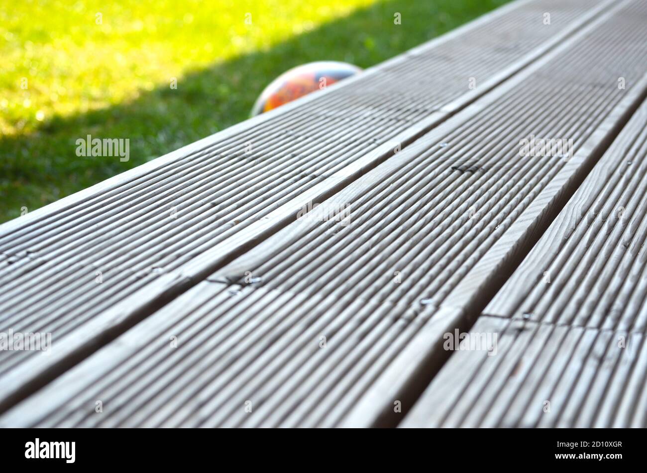 Close up of exterior wooden terrace floor slightly above lawn. Part of ...