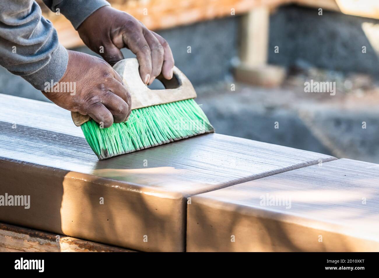 Construction Worker Using Brush On Wet Cement Forming Coping Around New ...