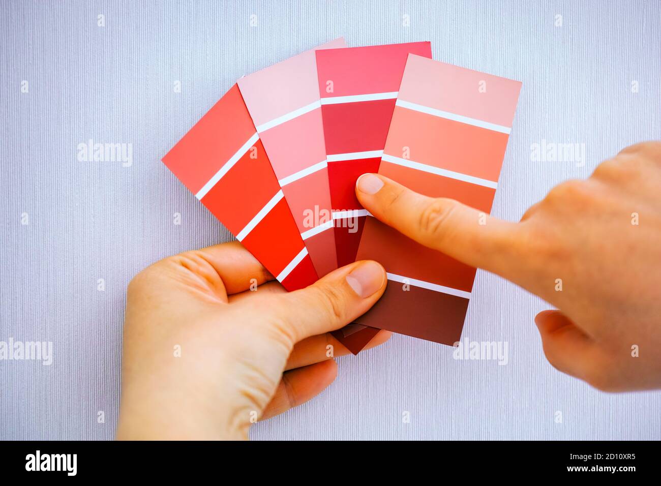 Woman choosing red colour from color swatches against wall Stock Photo ...