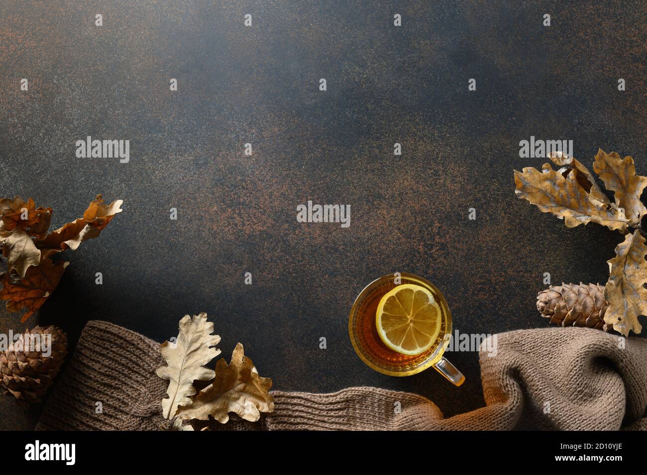 Fall cozy border with warming tea, knitted sweater and dry oak leaves ...