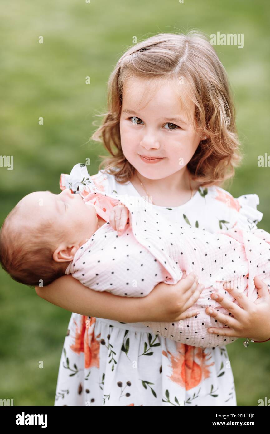 Cute Little Girl Holding Her Younger Newborn Sister Outdoors Relations