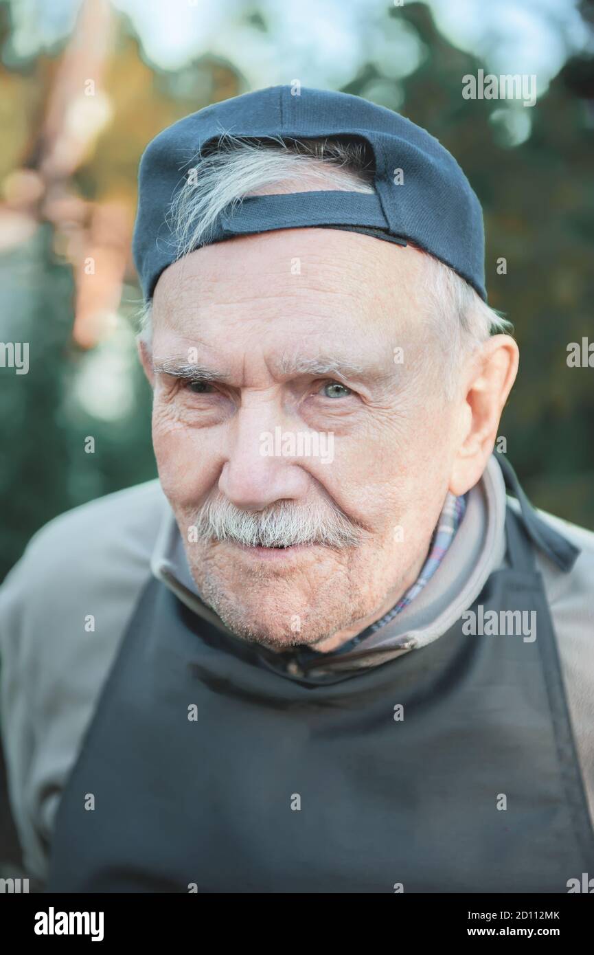 Portrait of an old farmer in a baseball cap. The 87 - year-old smiles ...