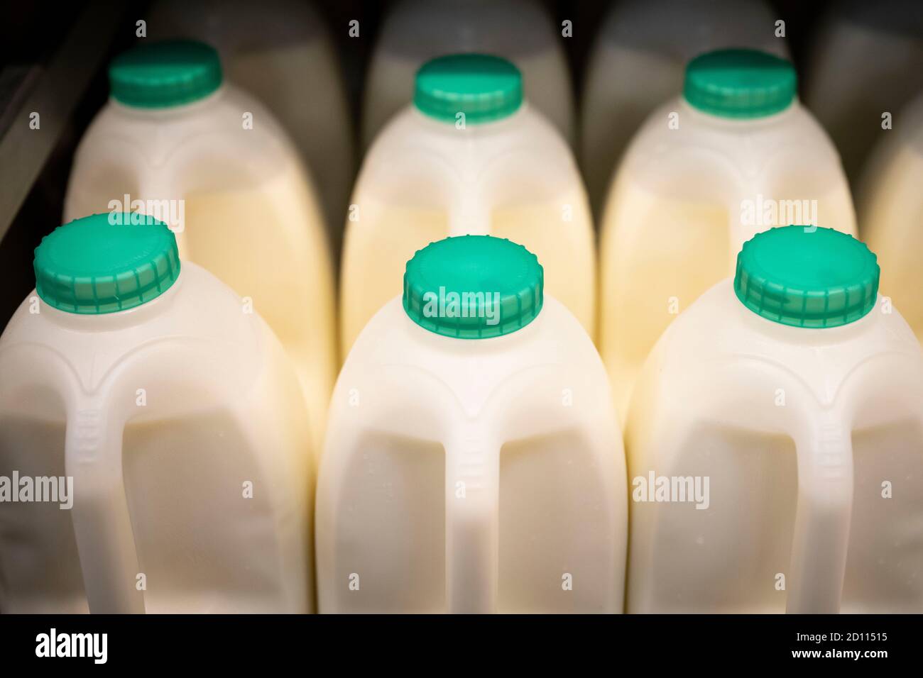 A top down view of bottles of milk with green lids in a supermarket ...