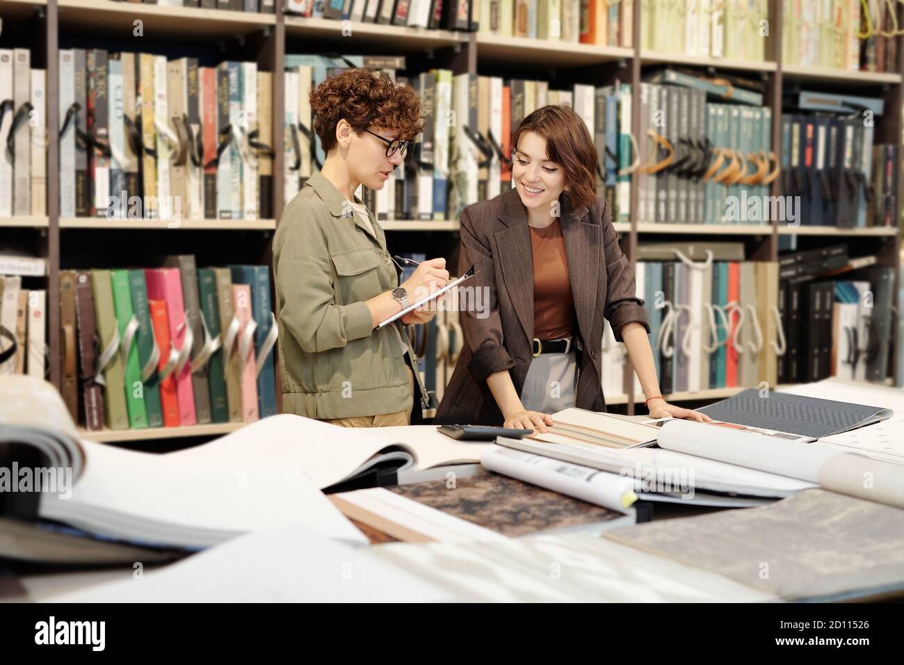 Young shop assistant making notes about color and texture of new ...
