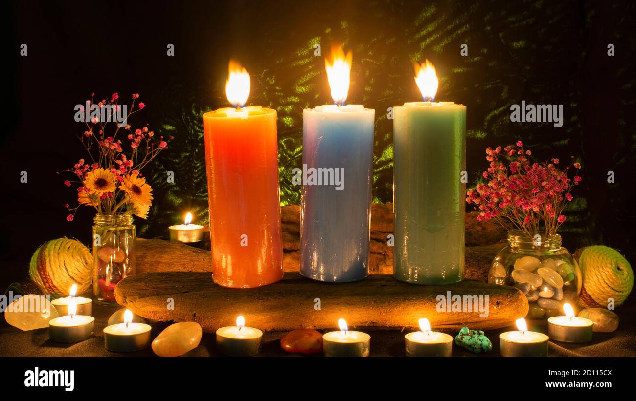 Composition with three large green, red and blue candles surrounded by ...