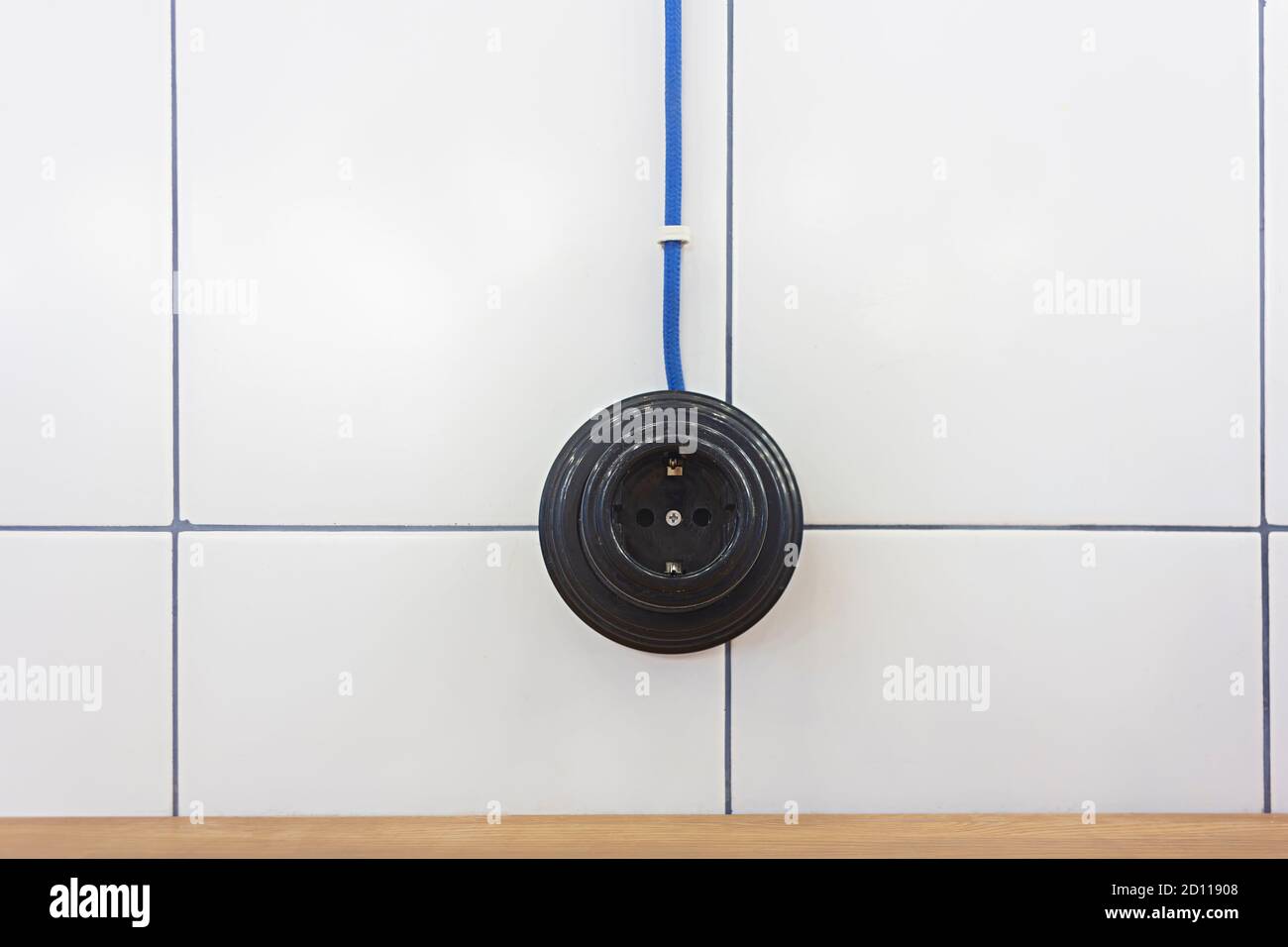 Old black electric EU power socket on a background of white ceramic ...