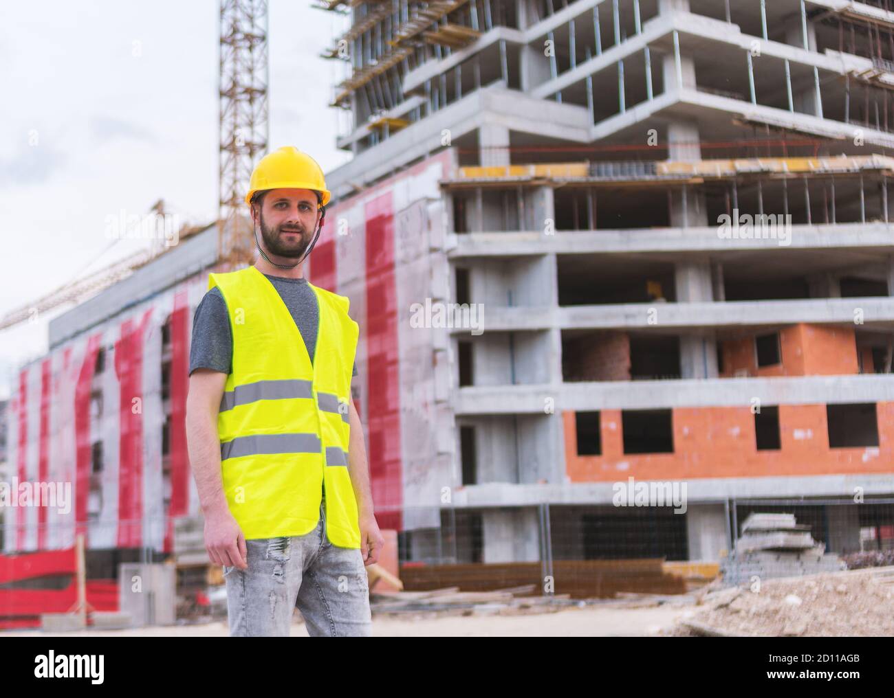 An engineer posing in front of building construction he is working of ...