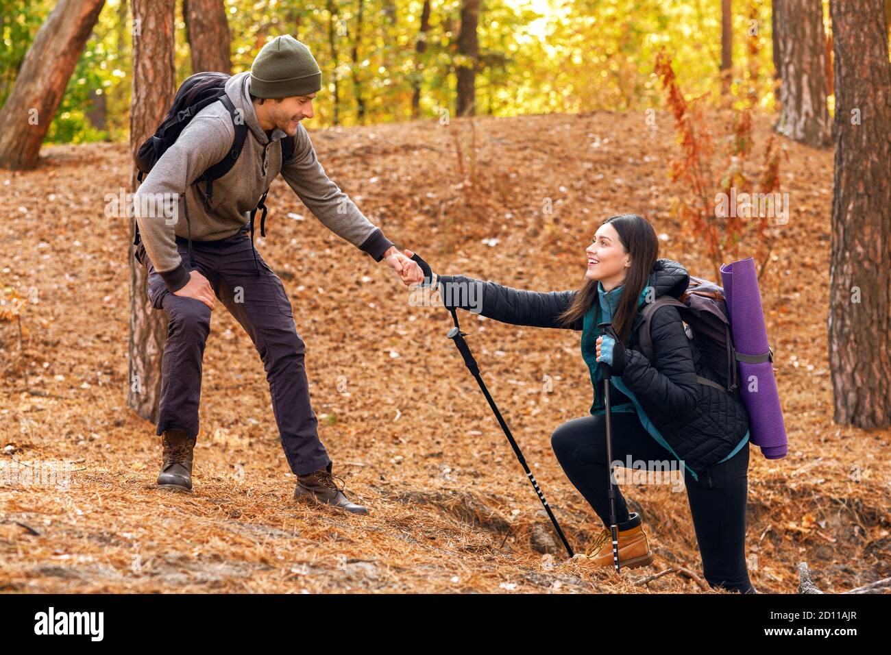 Handsome hiker helping his girlfriend uphill in forest Stock Photo - Alamy