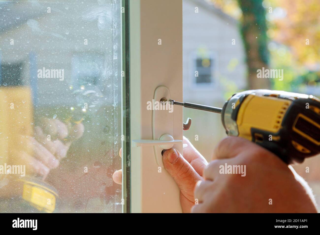 Handyman using a screwdriver drill to installing lock in door in a ...