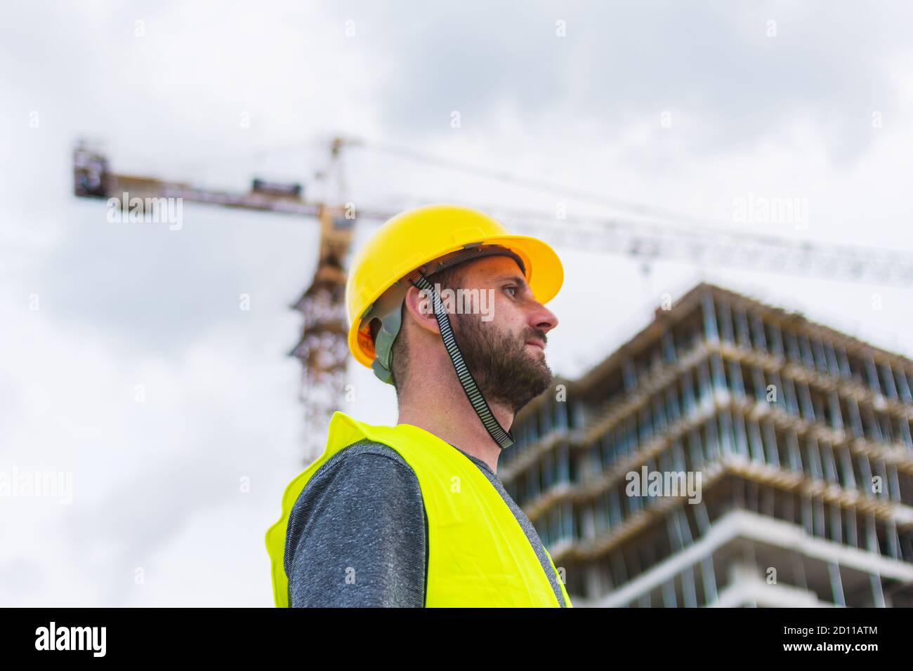An engineer posing in front of building construction he is working of ...