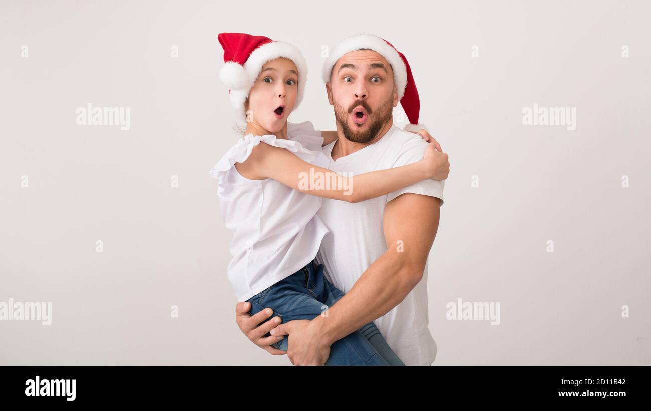 Shocked dad with daughter in Santa hats on white background Stock Photo ...