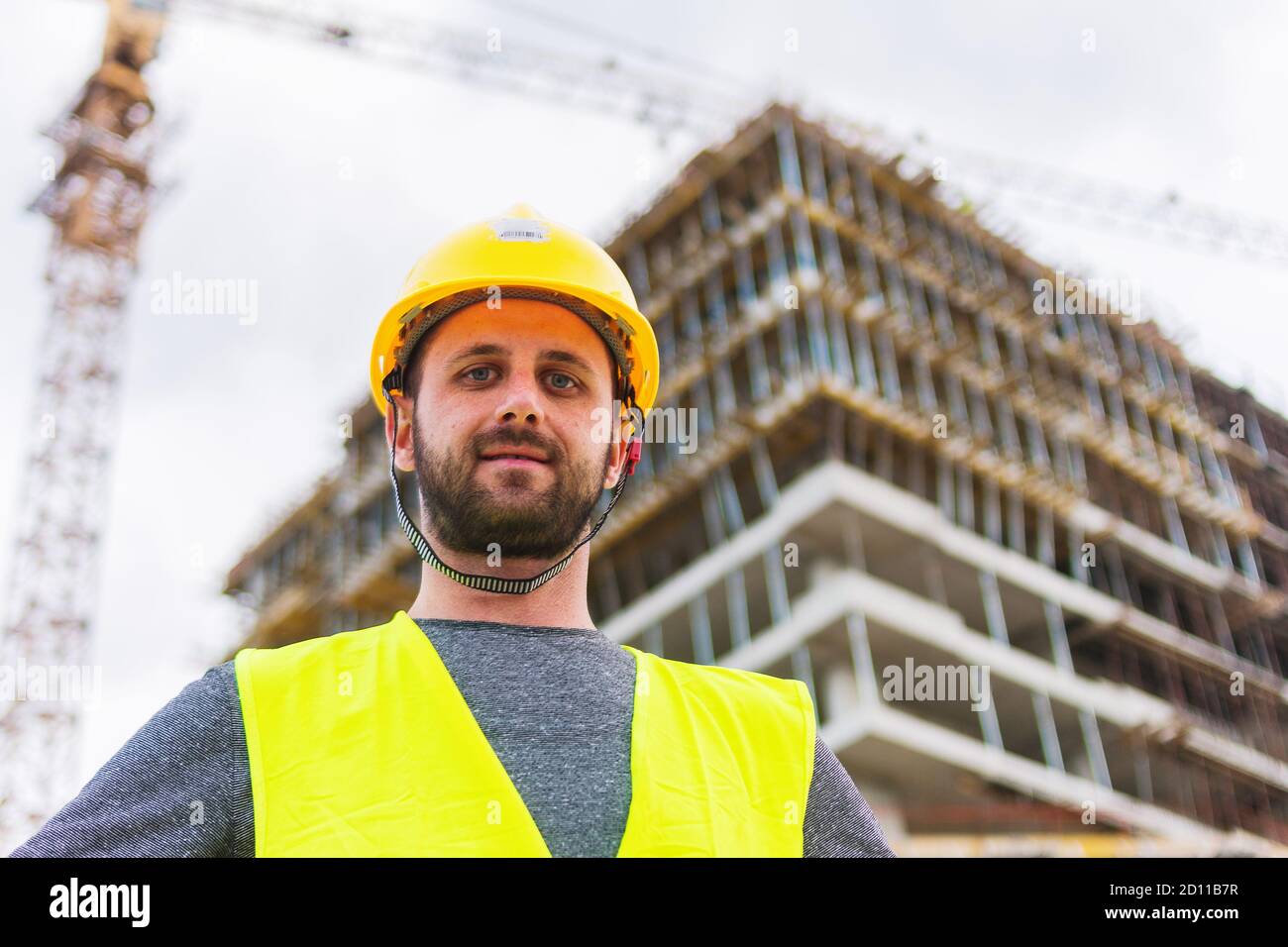An engineer posing in front of building construction he is working of ...