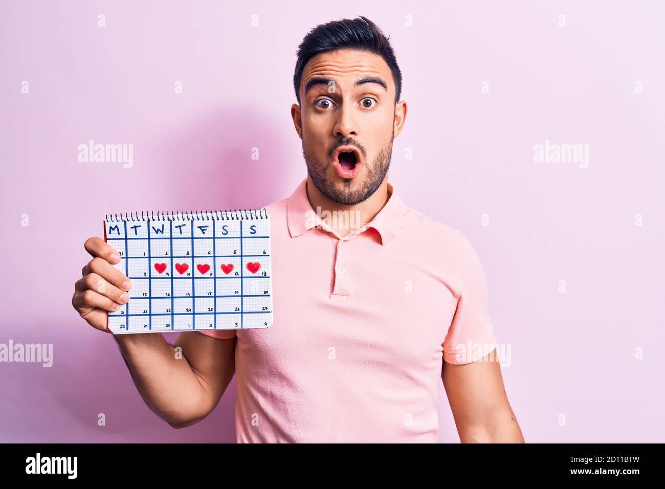 Handsome romantic man with beard holding calendar with red hearts over ...