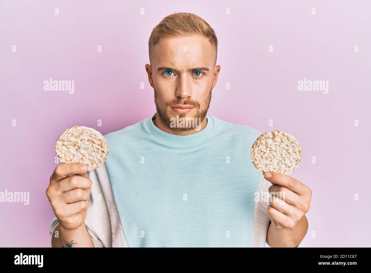 Young caucasian man eating healthy rice crackers depressed and worry ...