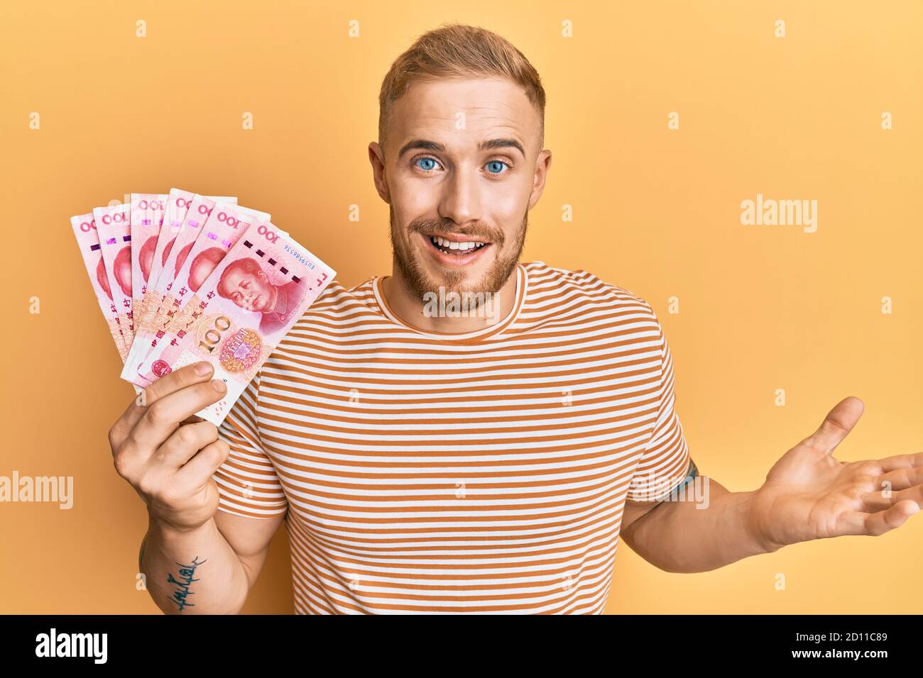 Young caucasian man holding 100 yuan chinese banknotes celebrating ...