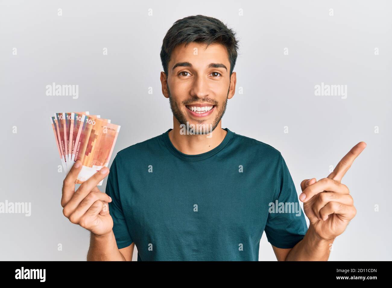 Young handsome man holding 100 norwegian krone banknotes smiling happy ...