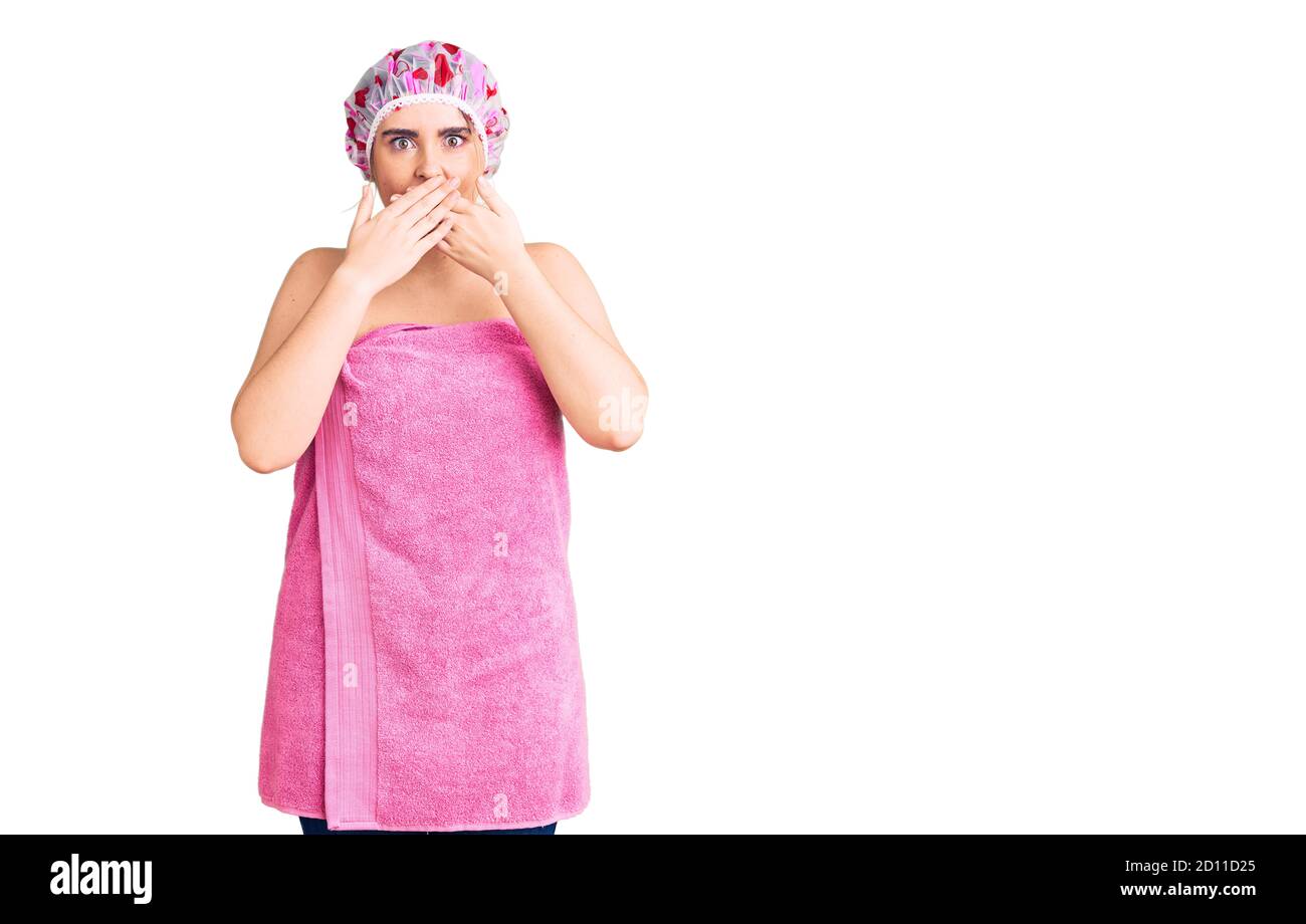 Young caucasian woman wearing shower cap and towel shocked covering ...