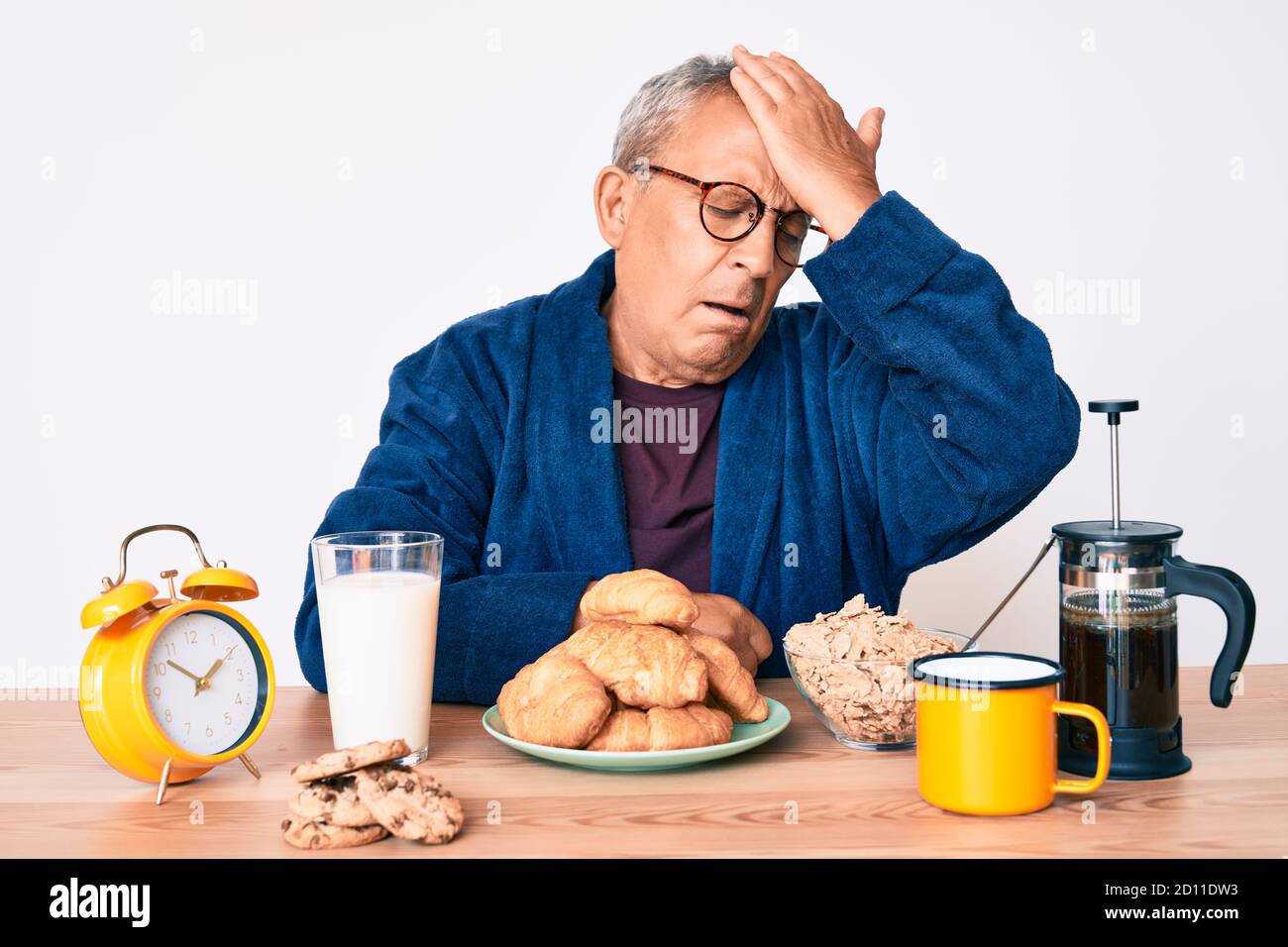 Senior handsome man with gray hair sitting on the table eating ...
