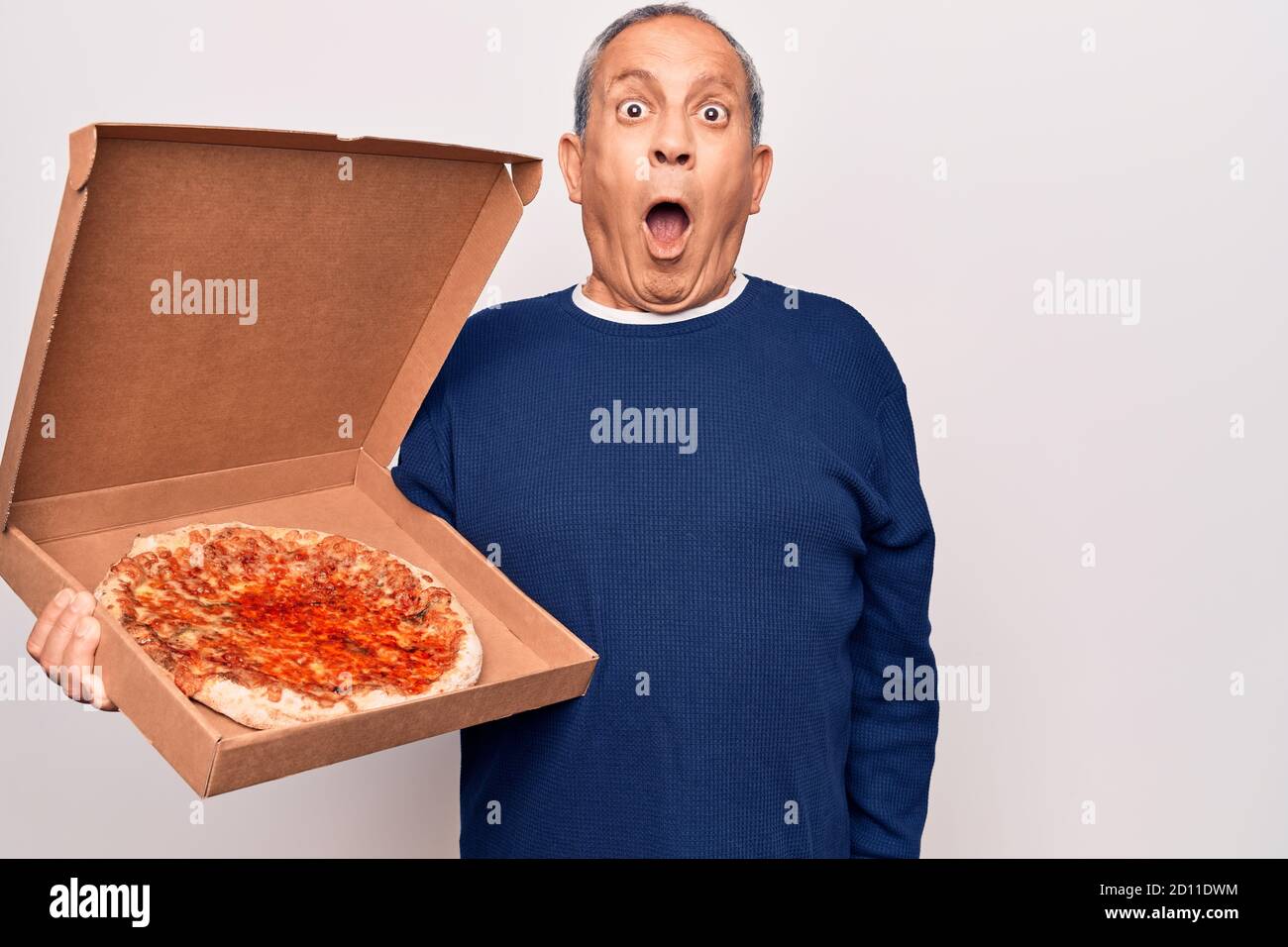 Senior man with grey hair holding delivery box of italian pizza scared ...